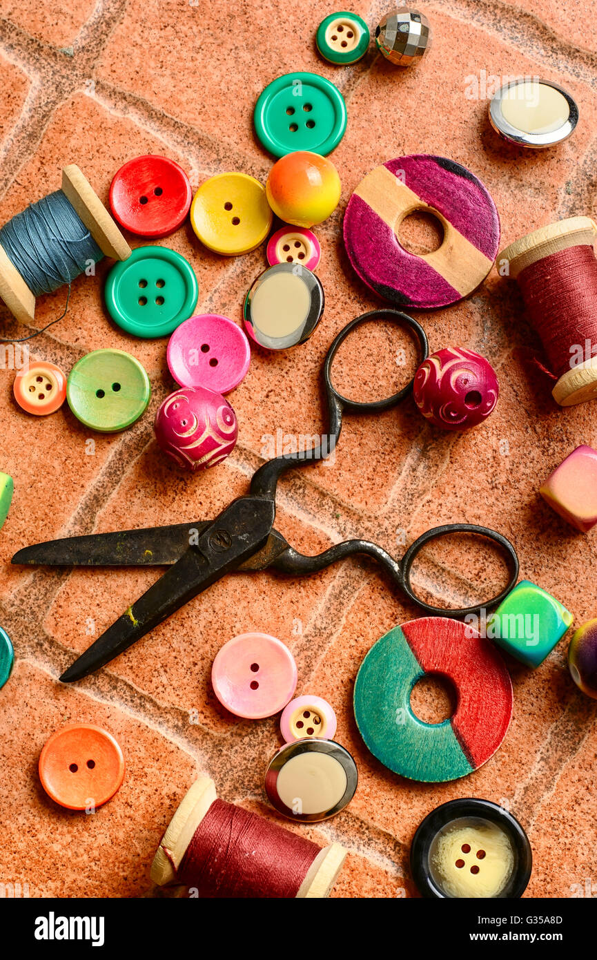 Sewing kit from buttons,beads and scissors on the brick background ...