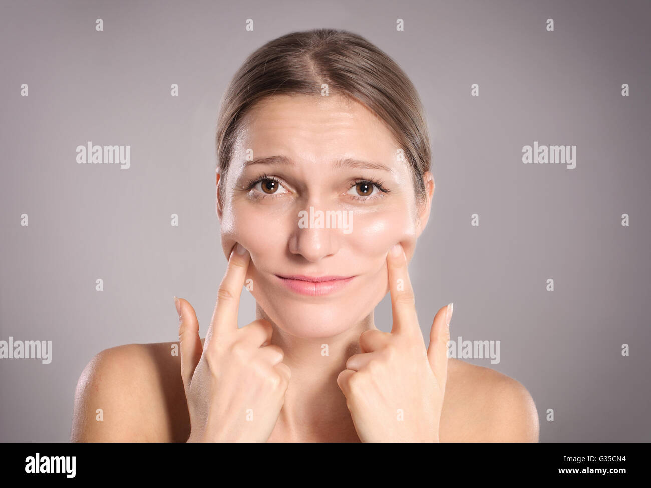 Forced smile. Young woman making a smile with her fingers Stock Photo ...