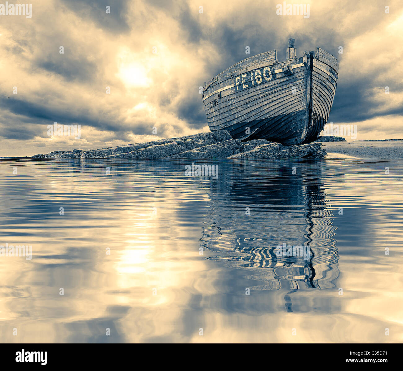 A shipwrecked boat stranded on the rocks with a low sun and great ...