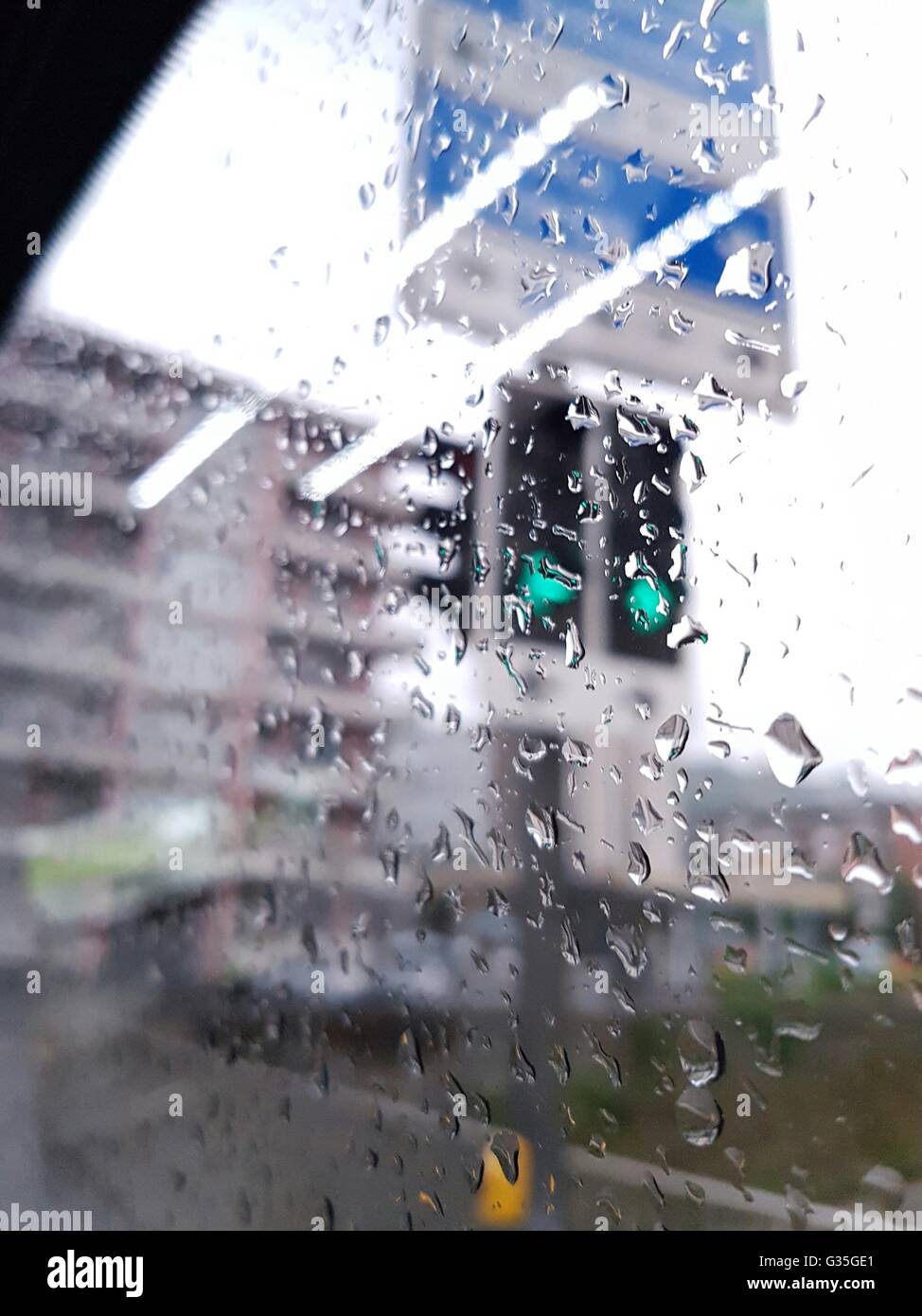 Street signs and green traffic lights in an urban area seen through wet ...