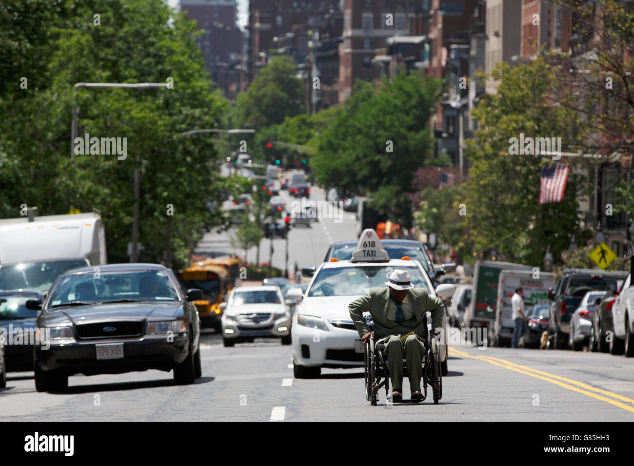 Man in a wheel chair rolls up Beacon Street in a traffic lane, Boston ...