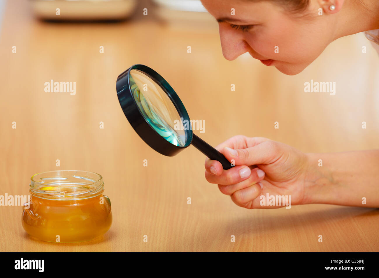 Mature woman female inspecting testing honey food with magnifying glass ...