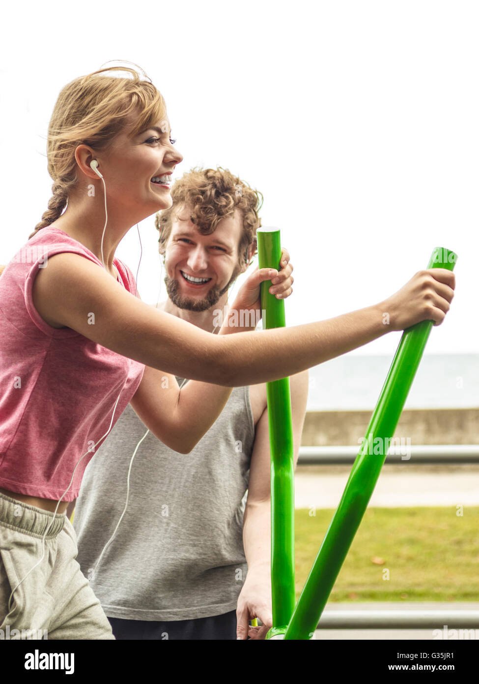 Happy active woman exercising on elliptical trainer machine and man ...