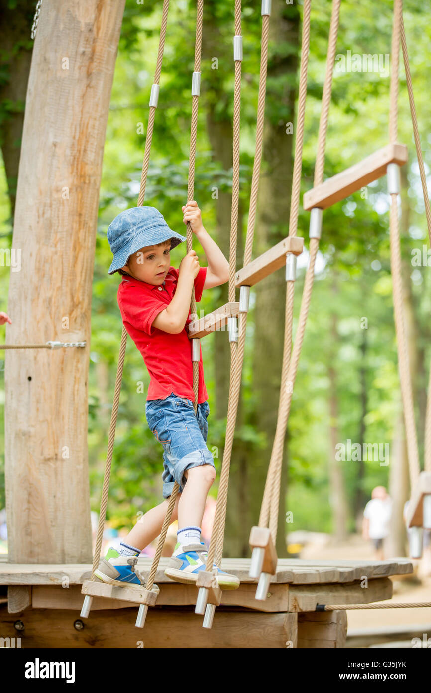 Cute child, boy, climbing in a rope playground structure, springtime ...