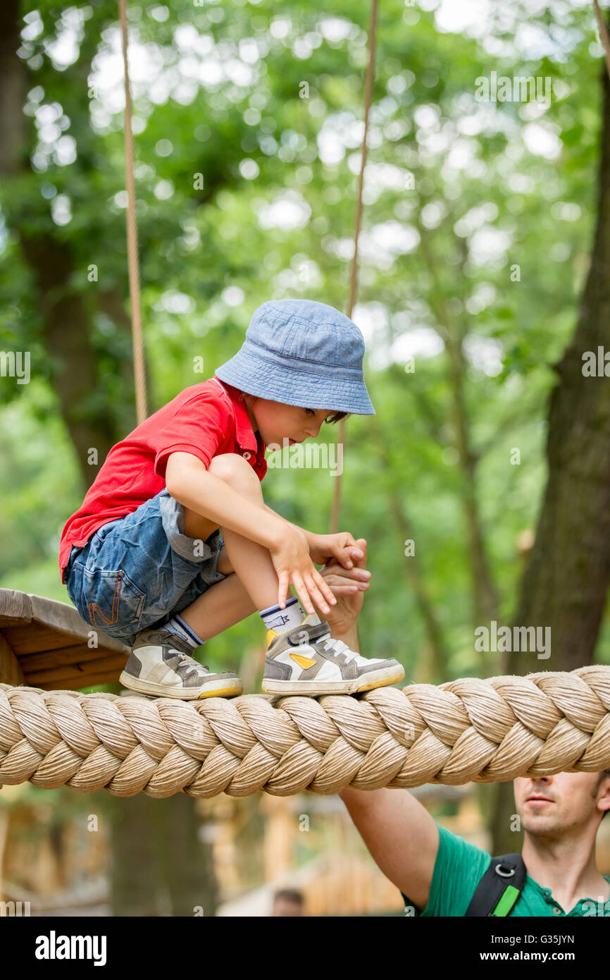 Cute child, boy, climbing in a rope playground structure, springtime ...
