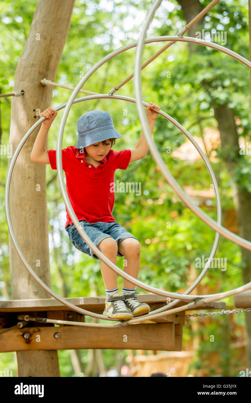 Cute child, boy, climbing in a rope playground structure, springtime ...