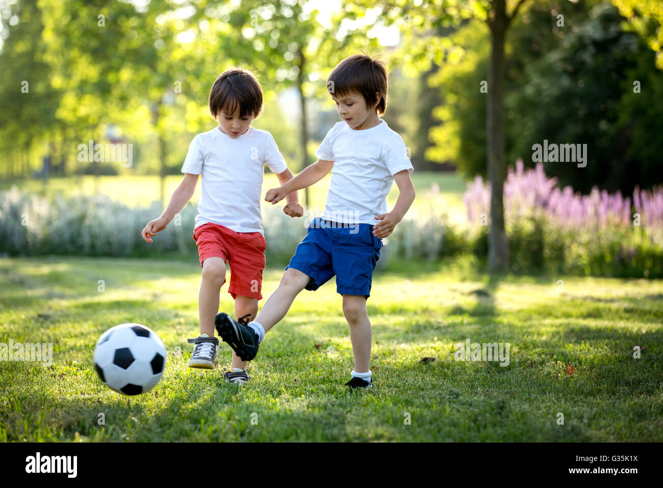 Two cute little kids, playing football together, summertime. Children ...