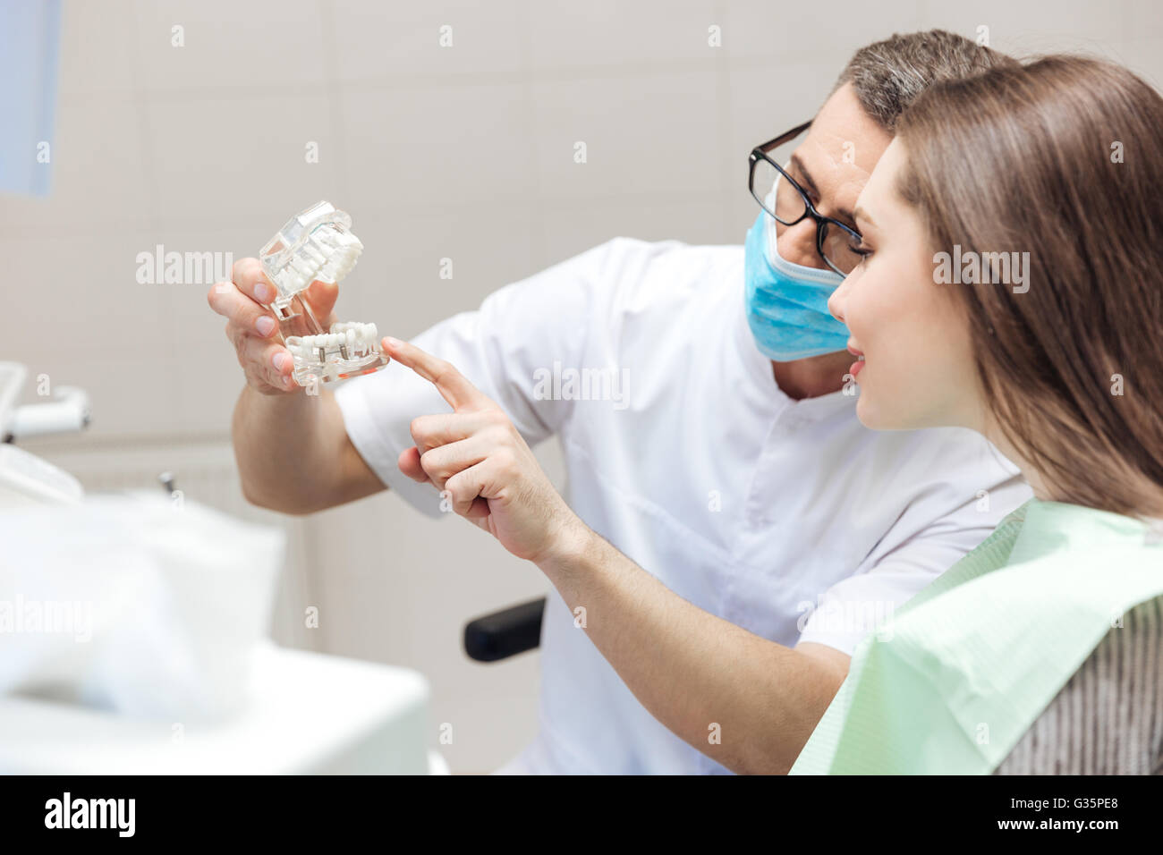 Man dentist show dentures teeth at dental surgery to his patient at the ...