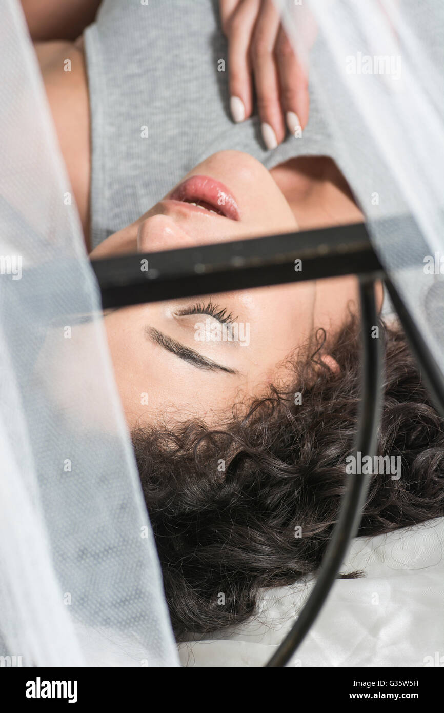 Young woman in bed hand over heart Stock Photo - Alamy