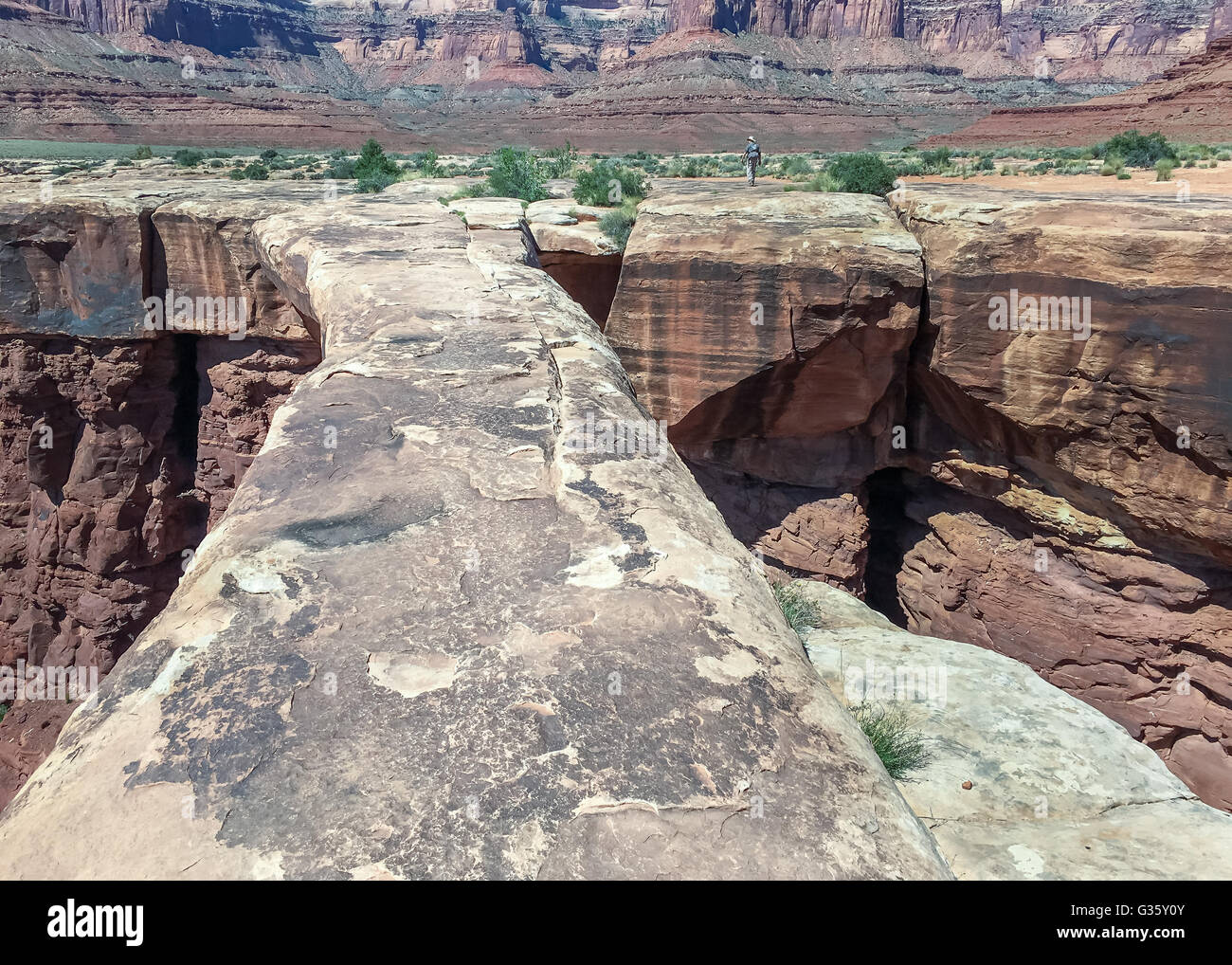 A hiker walking near the apex of Musselman Arch, on White Rim Road ...