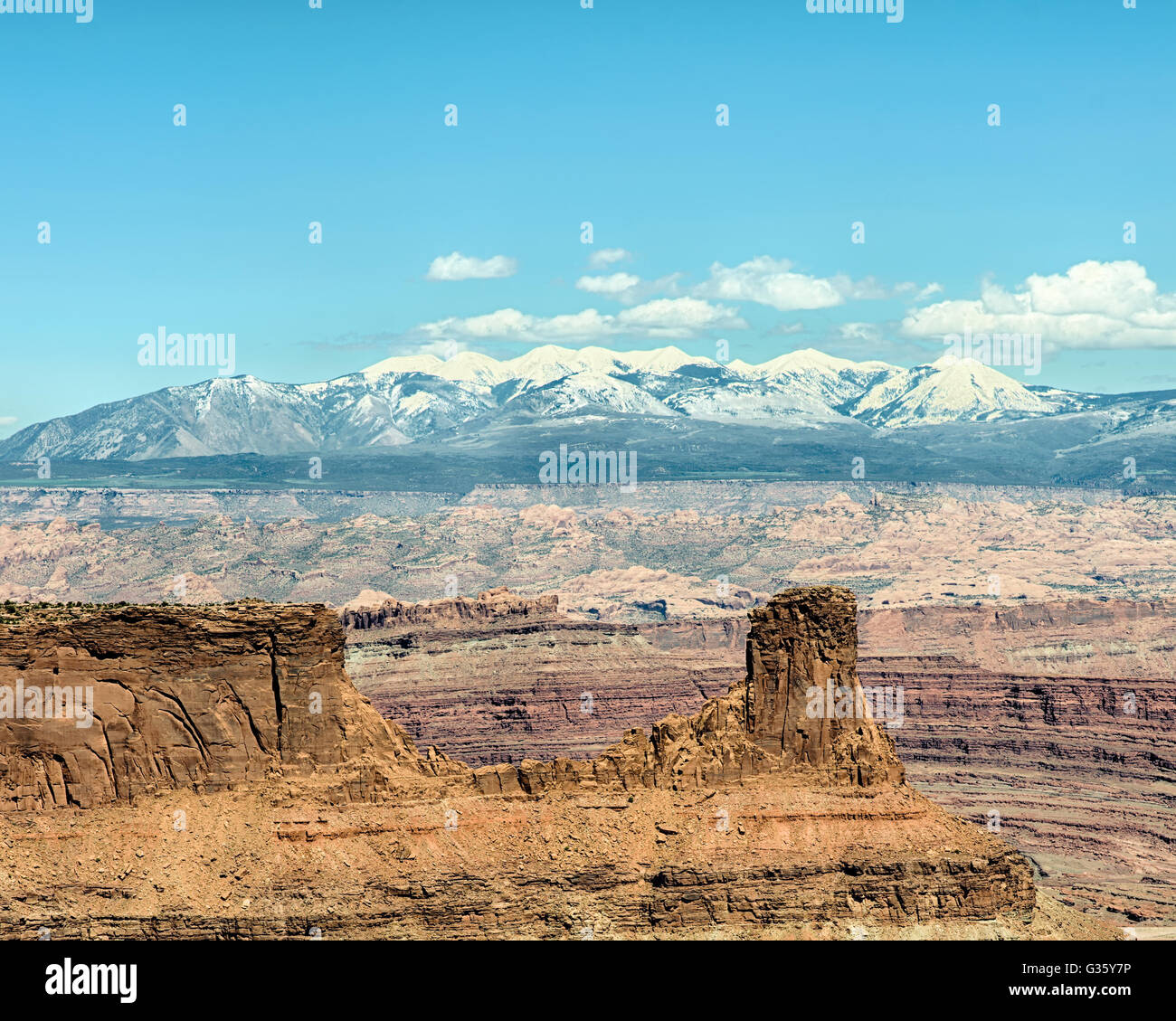 Snow-capped La Sal mountains rise above a butte on the East Rim Trail ...