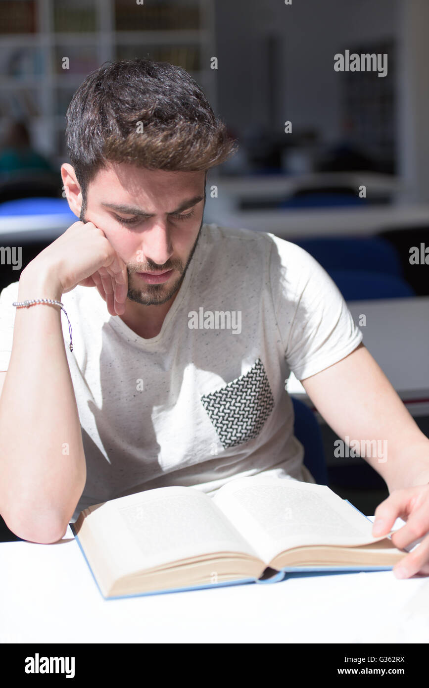 Student reading book in school library. Study lessons for exam. Hard ...