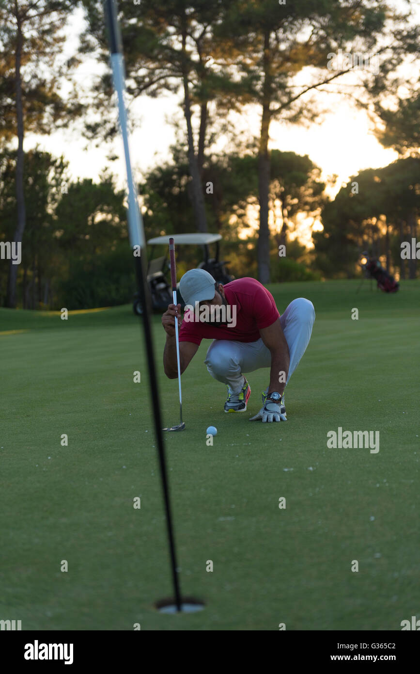golf player aiming shot with club on course at beautiful sunset with ...