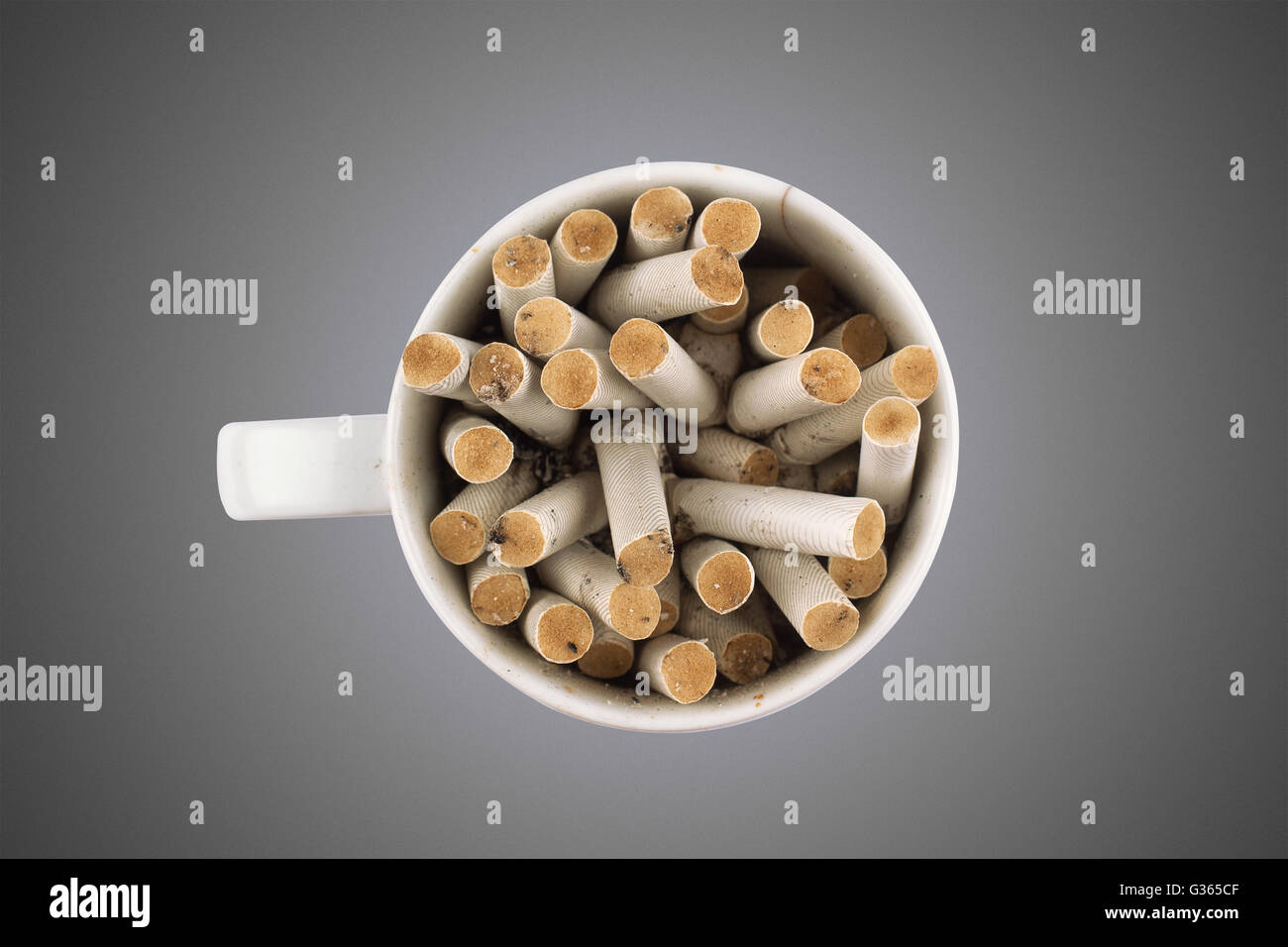 Horizontal top view of a white coffee cup full of cigarette butts ...