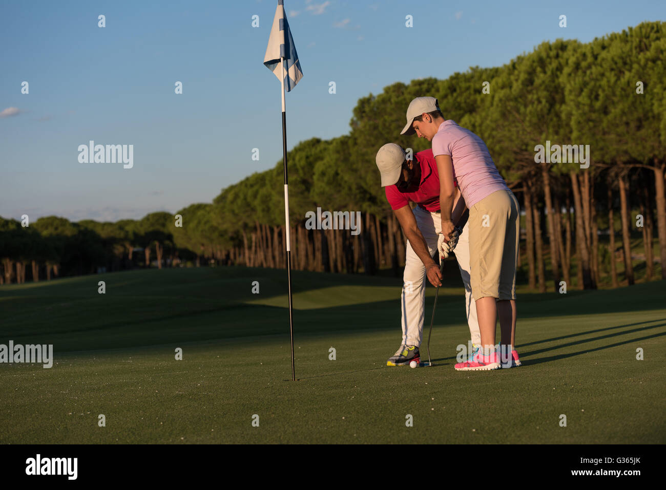 male golf instructor teaching female golf player, personal trainer ...