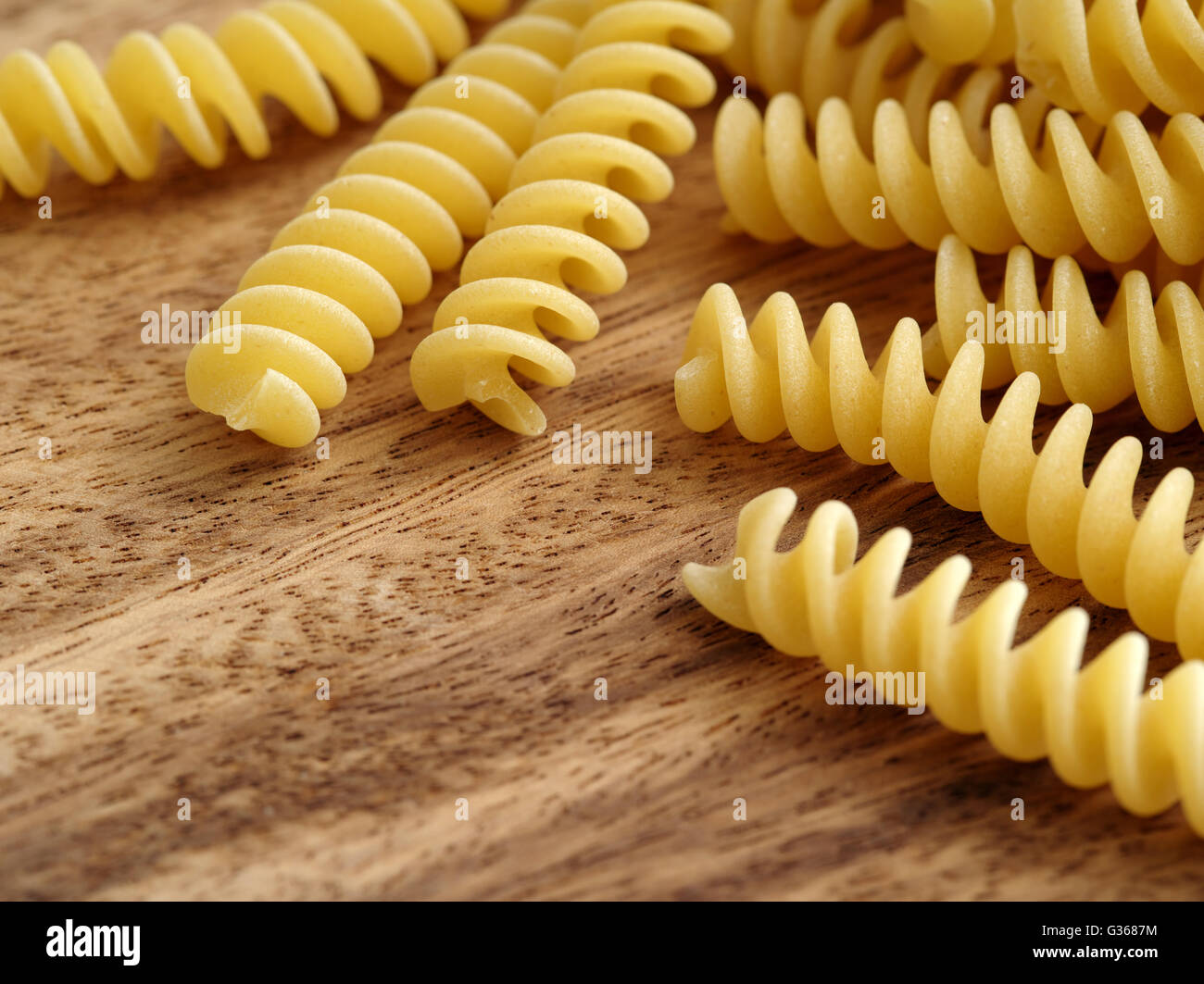 Closeup photo of fusilli dry pasta on a wood table Stock Photo - Alamy