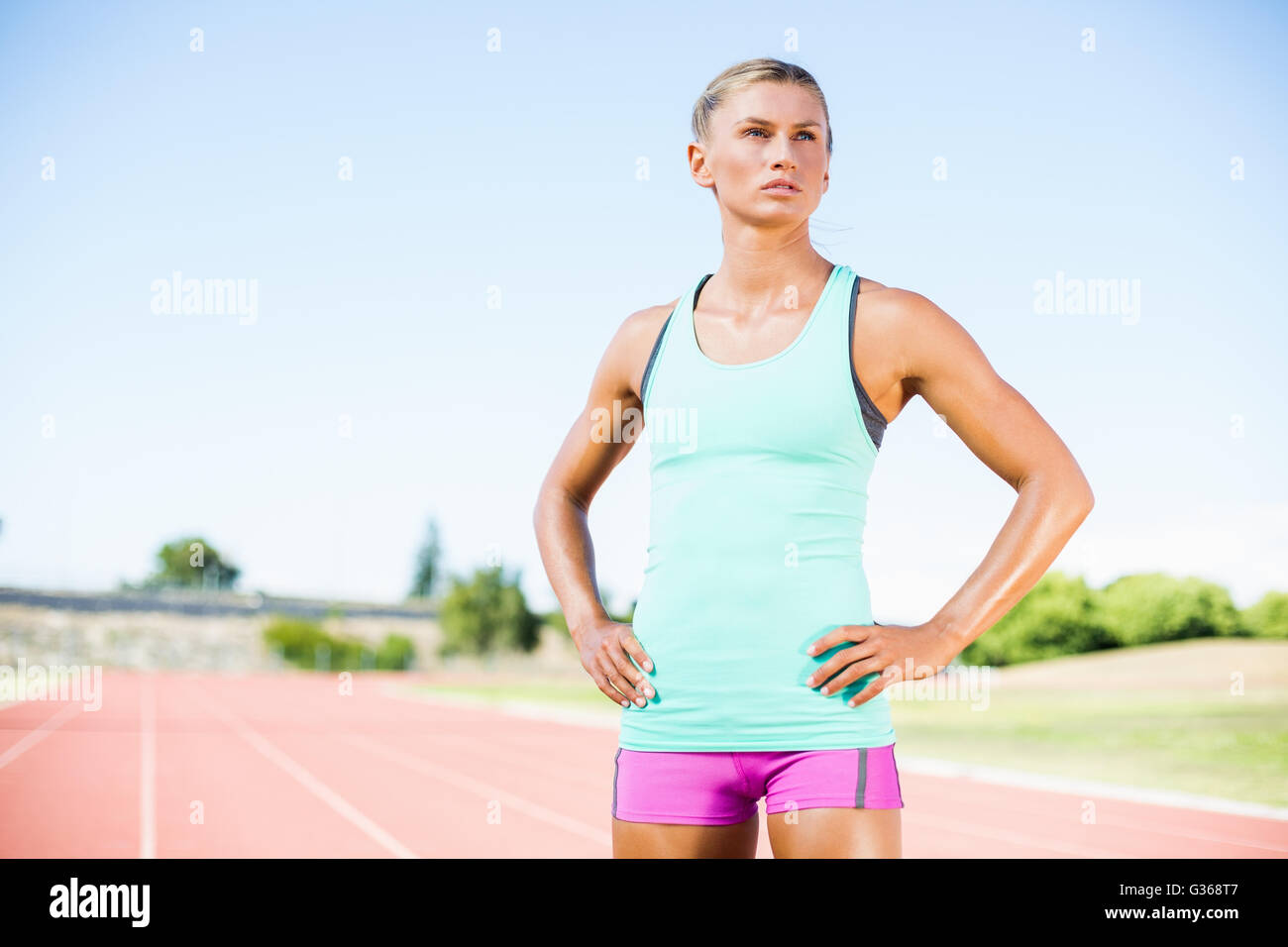 Tired female athlete standing on running track Stock Photo - Alamy