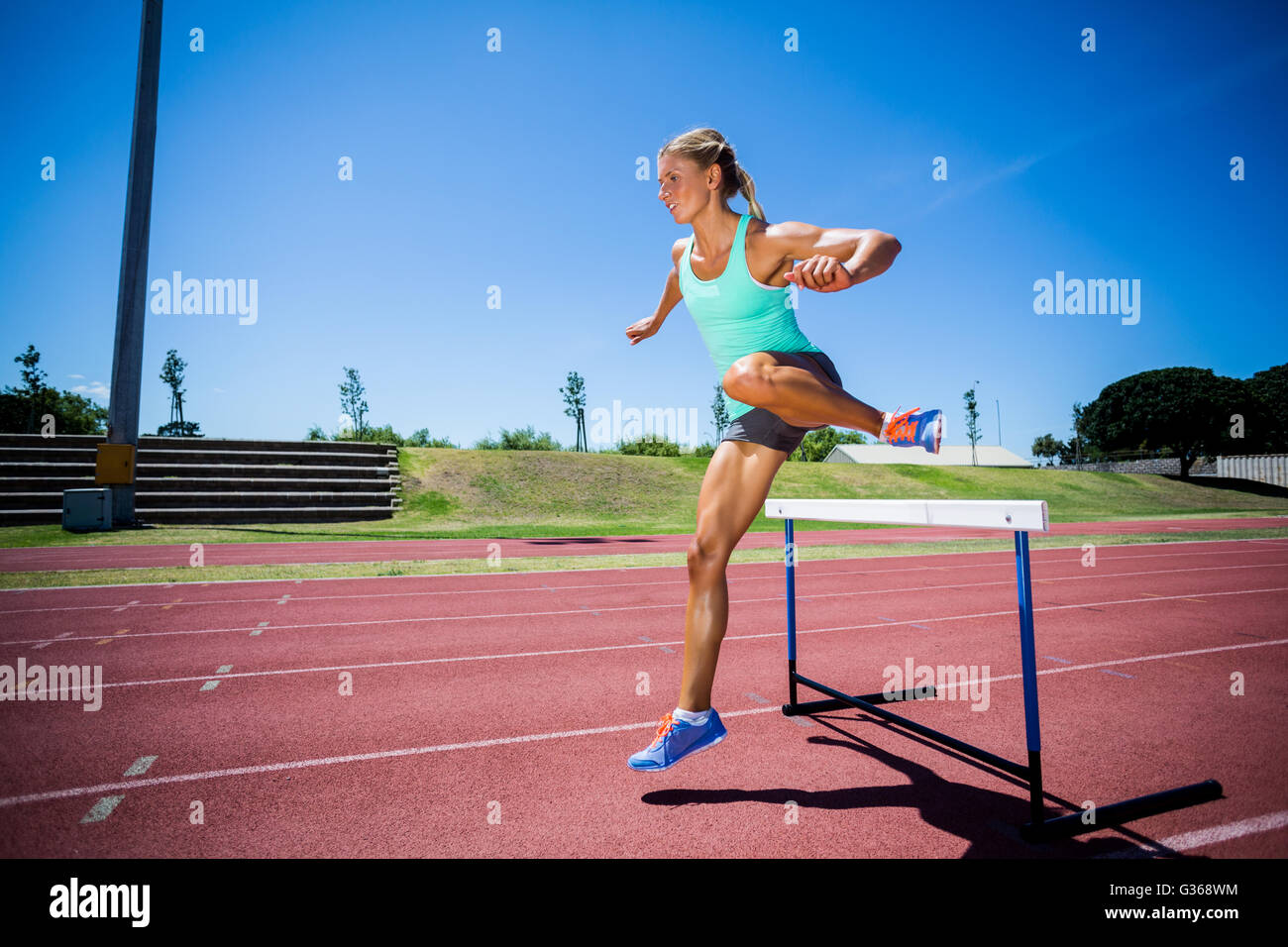 Female athlete jumping above the hurdle Stock Photo - Alamy