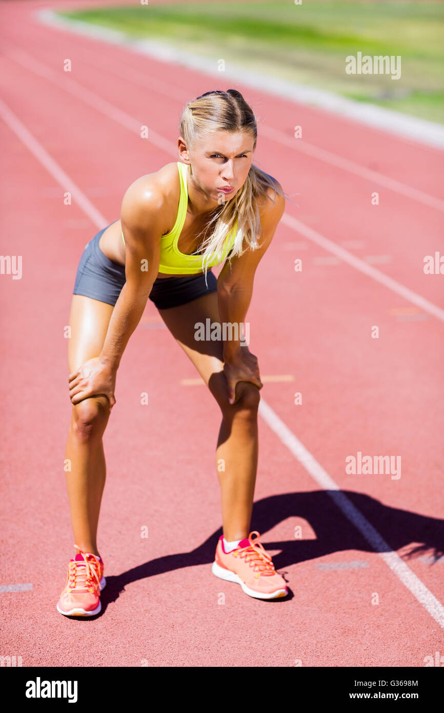 Tired female athlete standing on running track Stock Photo - Alamy