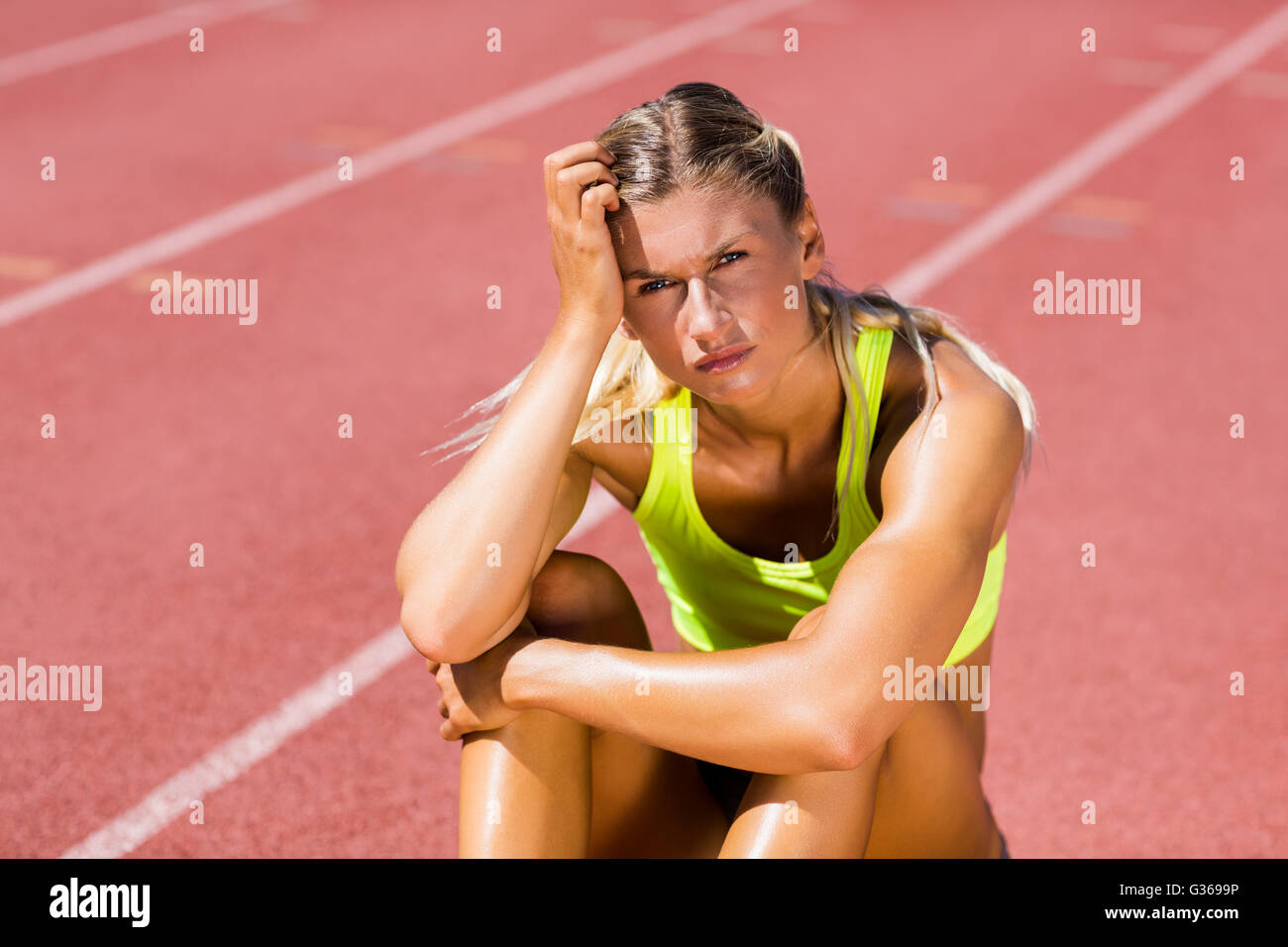 Upset female athlete sitting on running track Stock Photo - Alamy