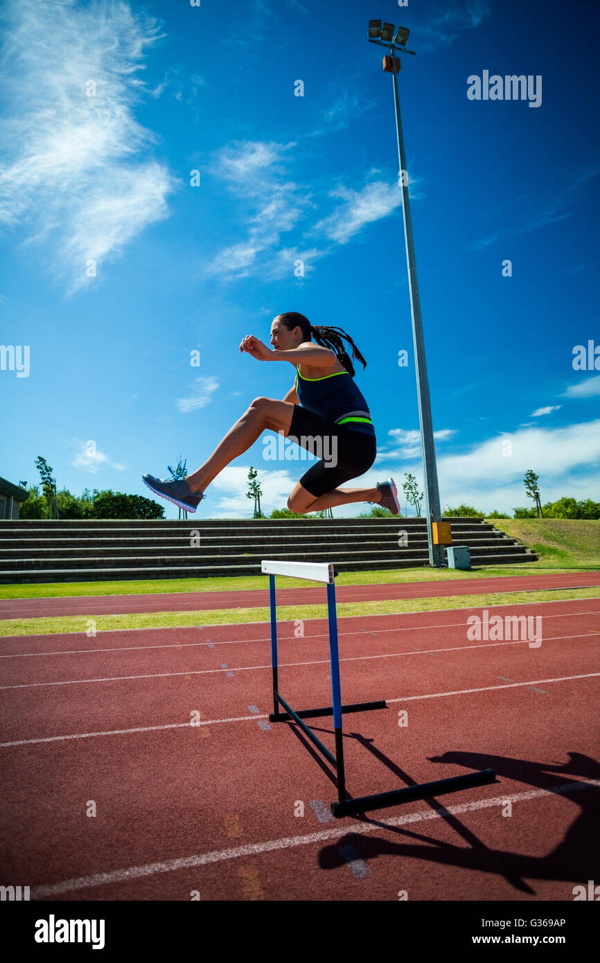 Female athlete jumping above the hurdle Stock Photo - Alamy