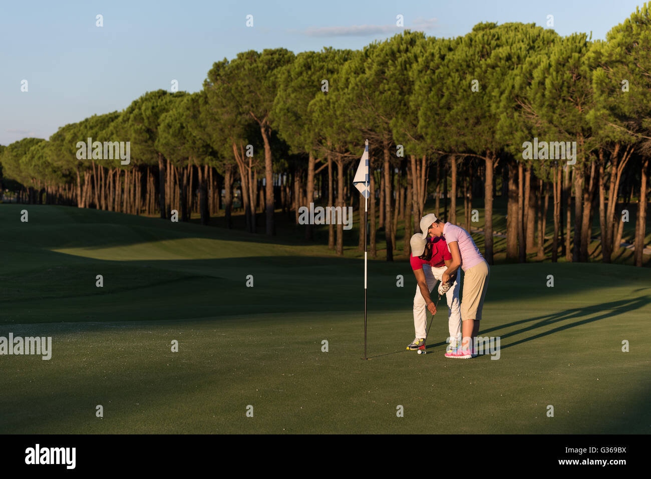 male golf instructor teaching female golf player, personal trainer ...