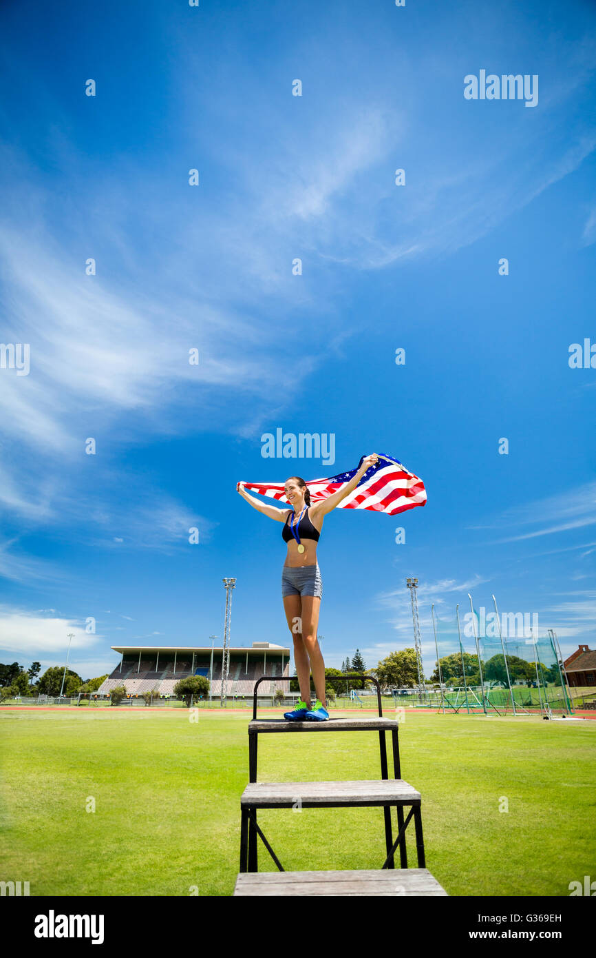 Happy female athlete holding up american flag Stock Photo - Alamy
