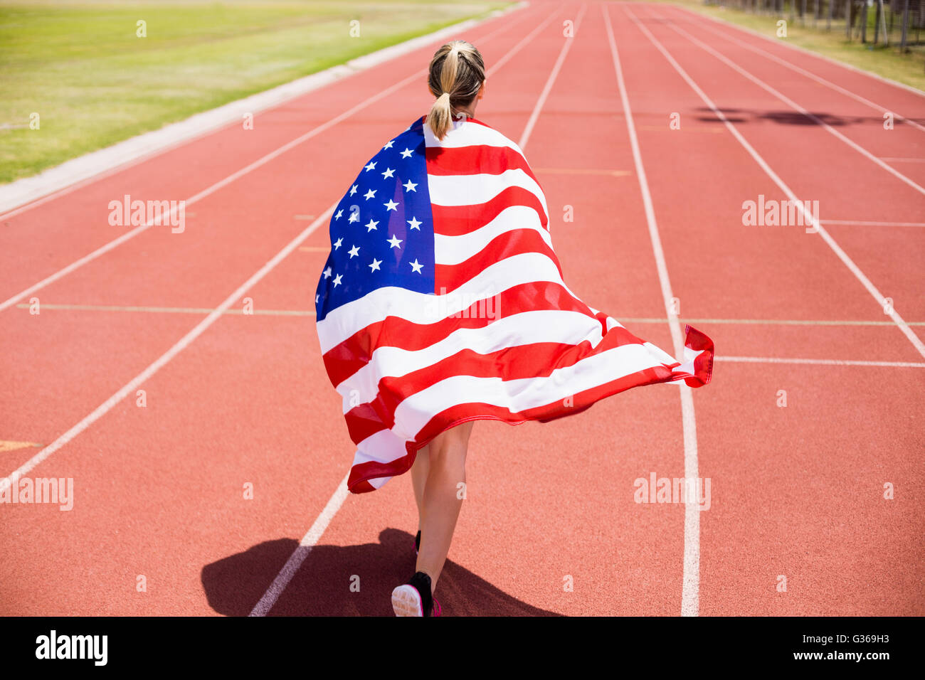 Rear view of female athlete running on the running track with american ...