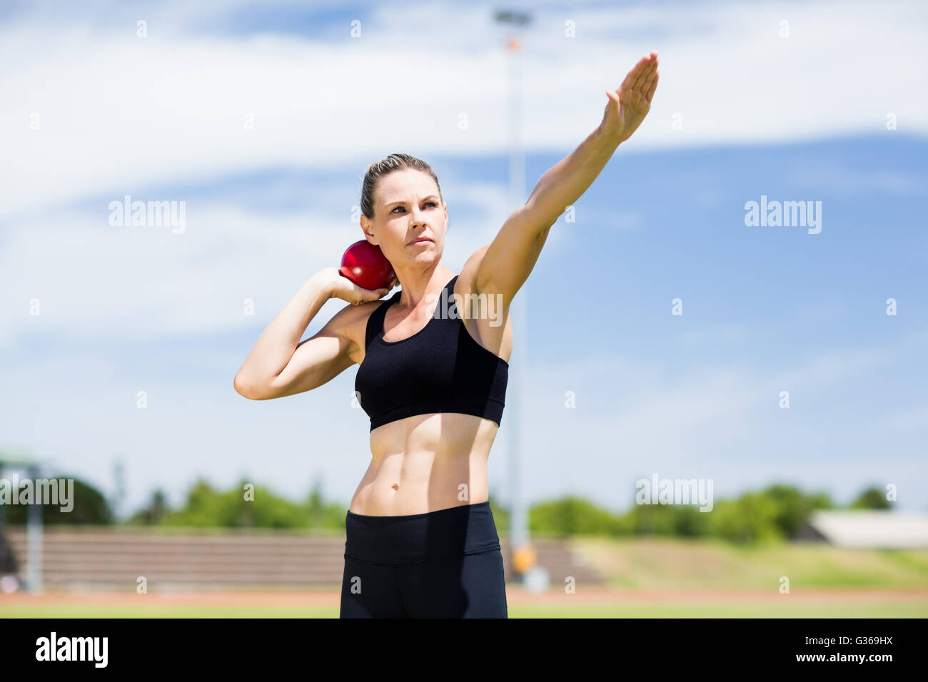 Confident female athlete preparing to throw shot put ball Stock Photo ...