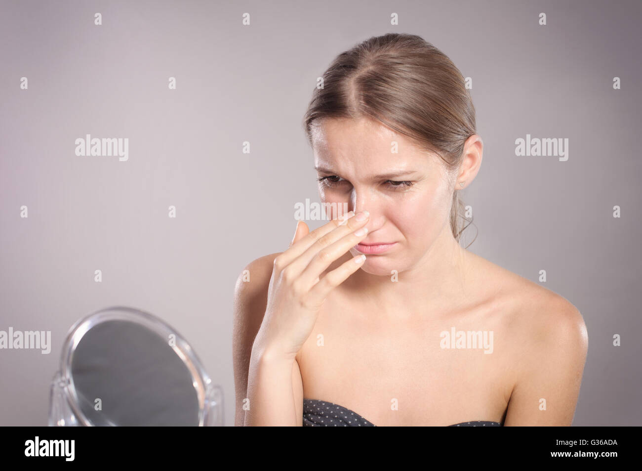 Young woman checks her nose in the mirror Stock Photo - Alamy