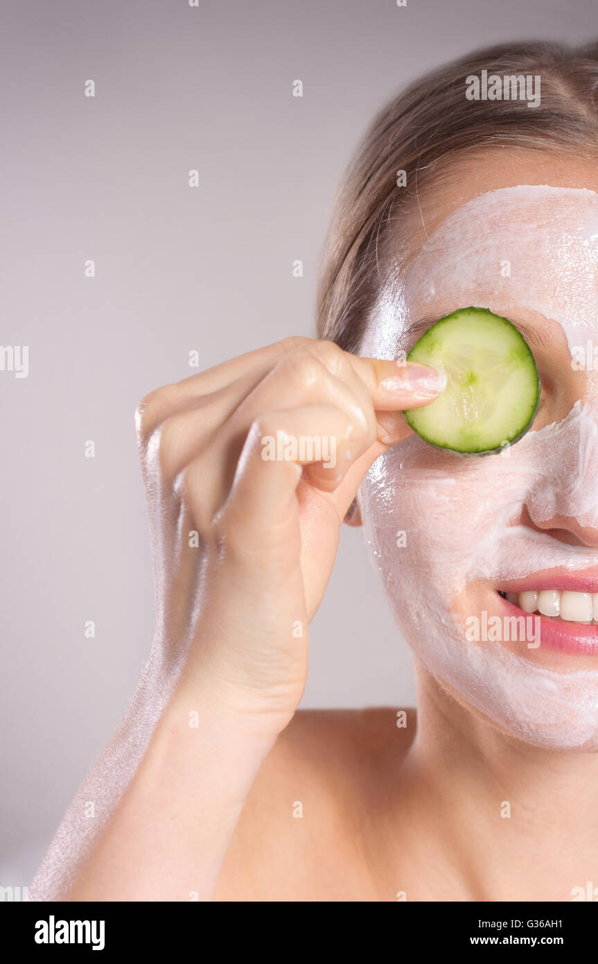 Beautiful young woman receiving facial mask of cucumber Stock Photo - Alamy