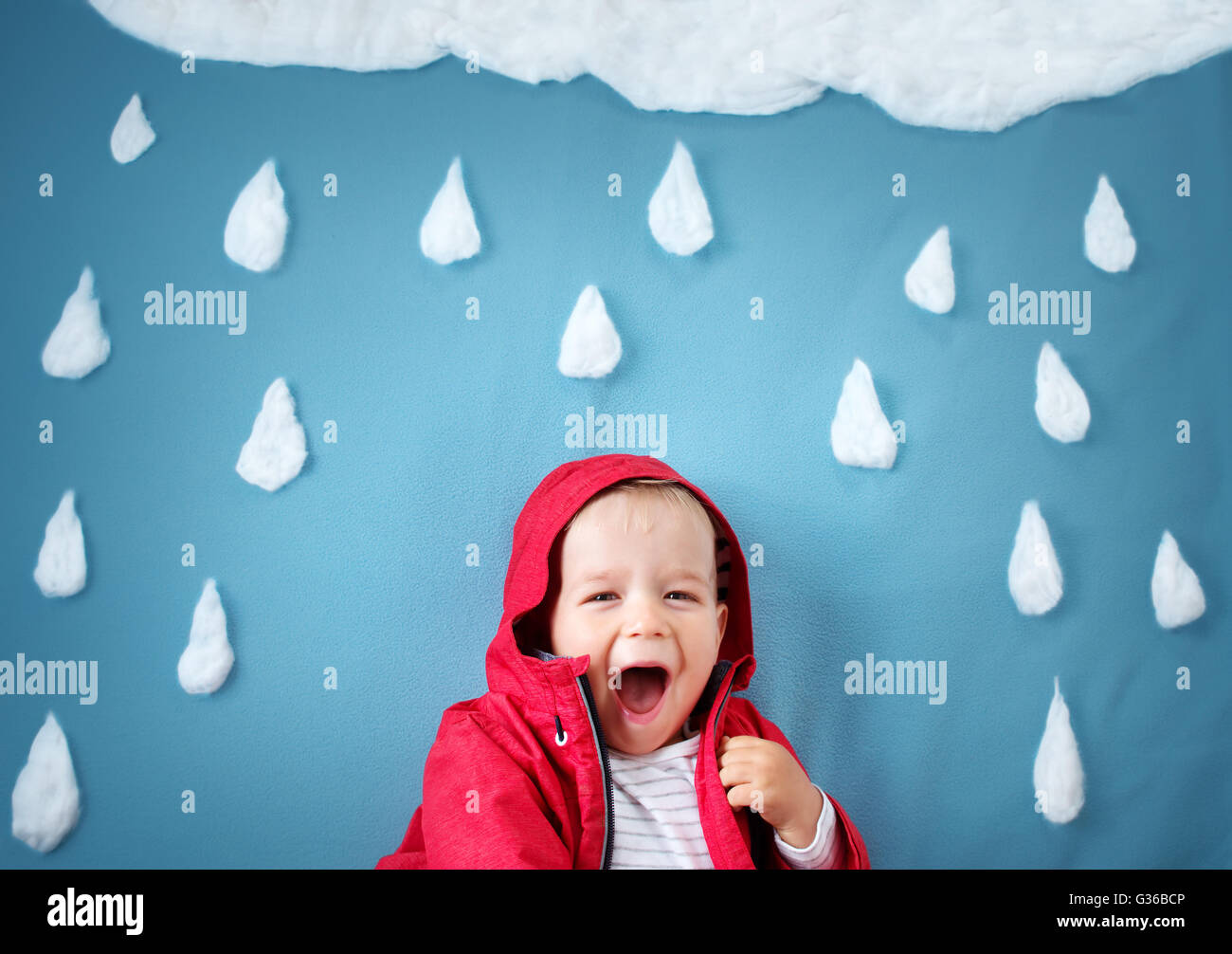 Little boy on blue background in coat with drop shapes Stock Photo - Alamy