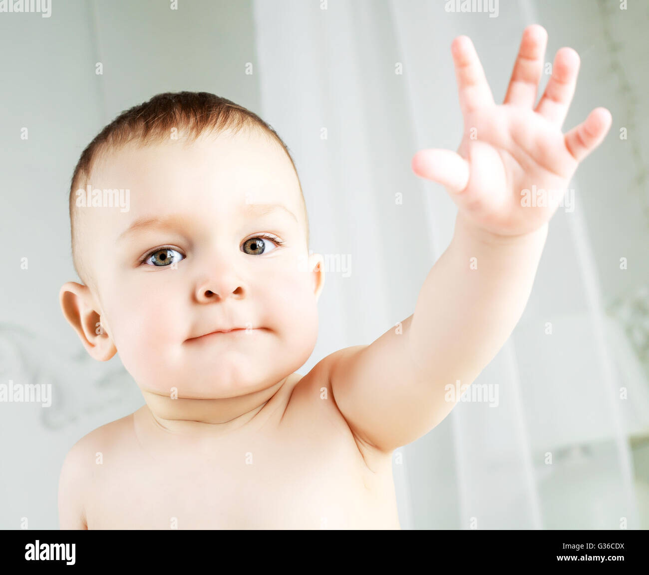 cute baby stretching his hand to us, in bed at home with a toy Stock ...