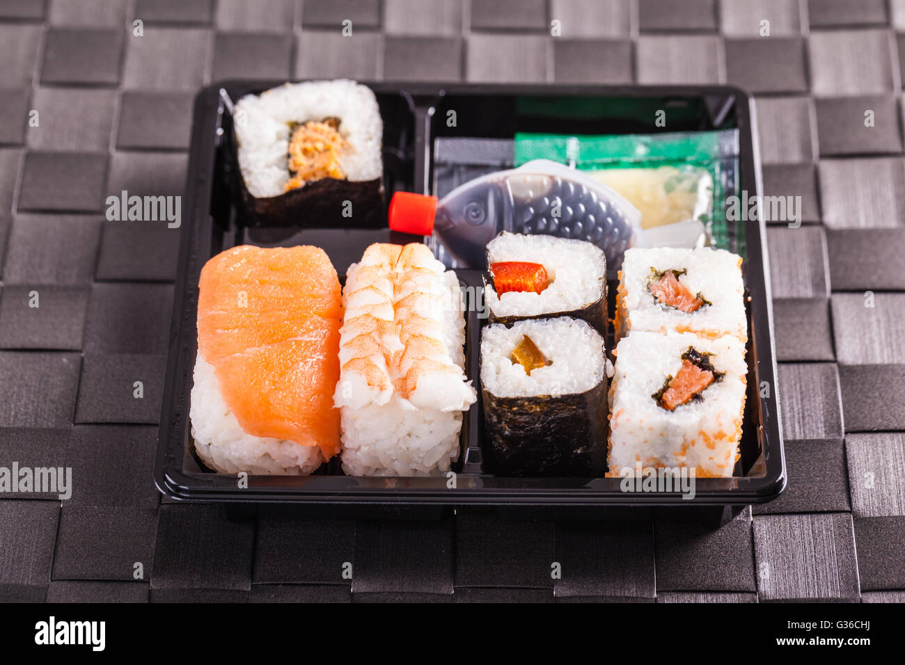 a sushi box or bento box with assorted sushi pieces over a dark black ...