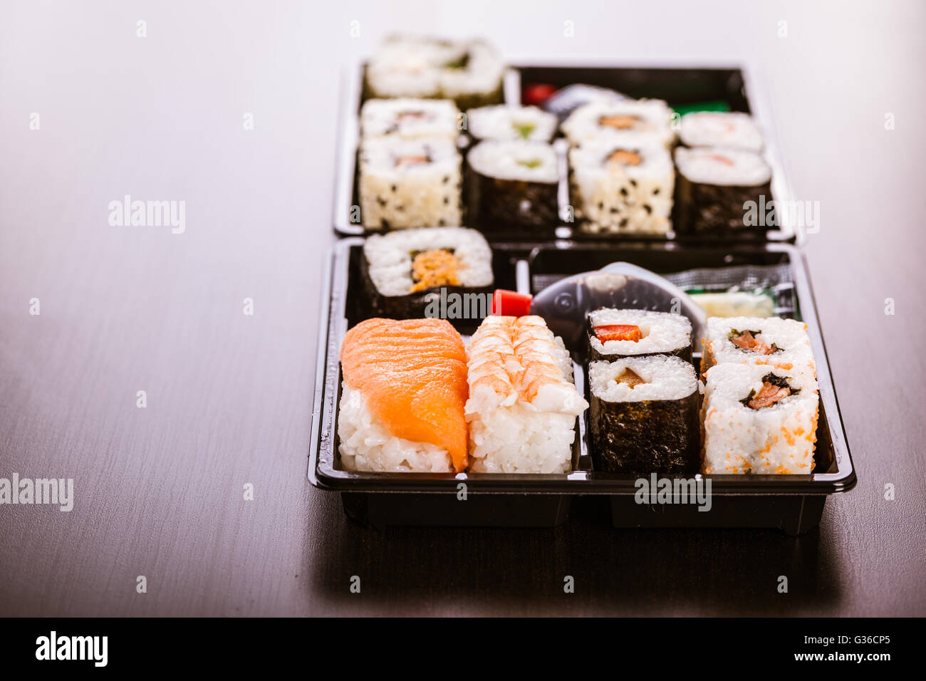 a sushi box or bento box with assorted sushi pieces over a dark wooden ...