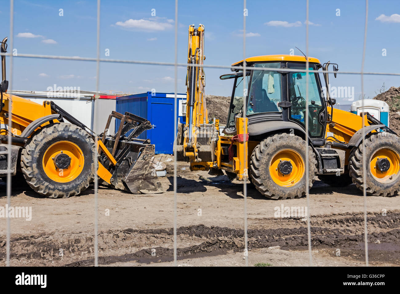 View on few excavators through a fence wire, parked at construction ...