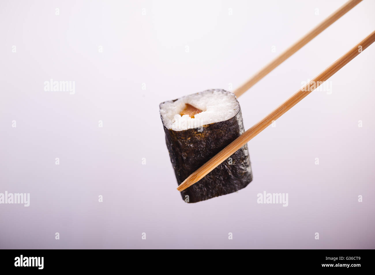 a maki sushi being picked up with chopsticks with copy space Stock Photo - Alamy