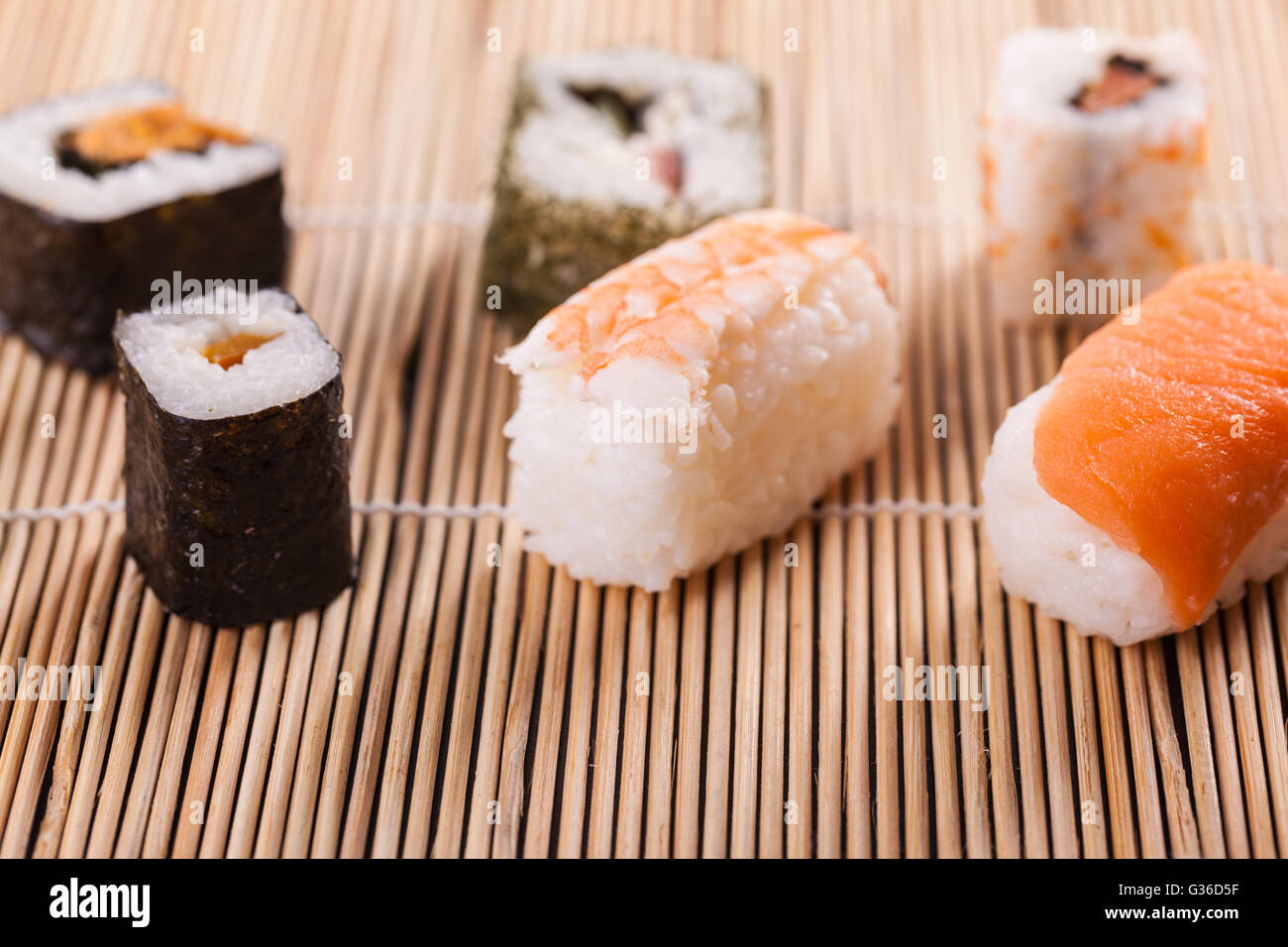 an assortment of different sushi pieces on a wooden bamboo sushi mat in ...