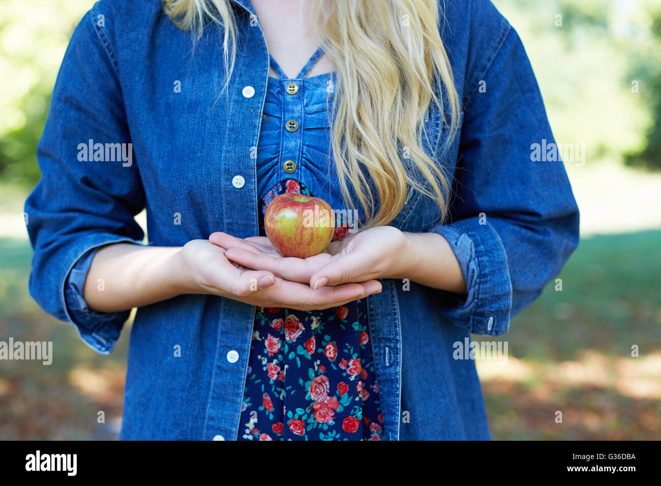 Apple woman. Very beautiful ethnic model eating red apple in the park ...