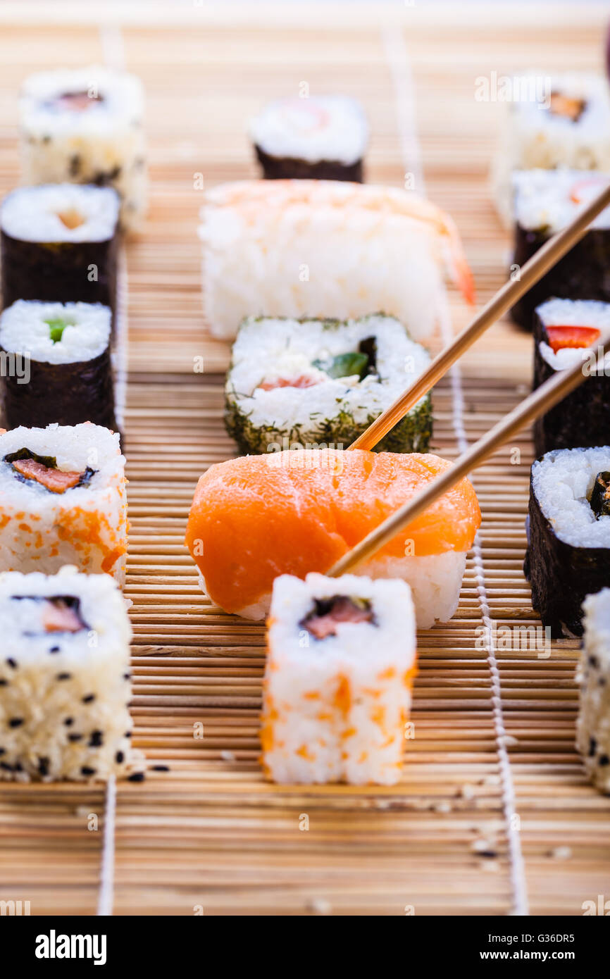 a salmon nigiri sushi being picked up with chopsticks with different ...