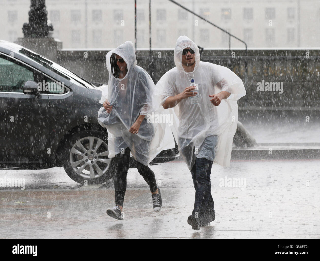 People are caught out in a heavy rain shower in Westminster, London ...
