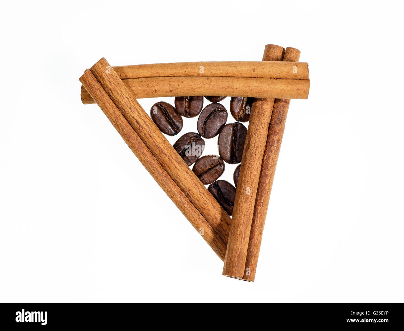 Roasted coffee beans in triangle of cinnamon sticks on white background ...
