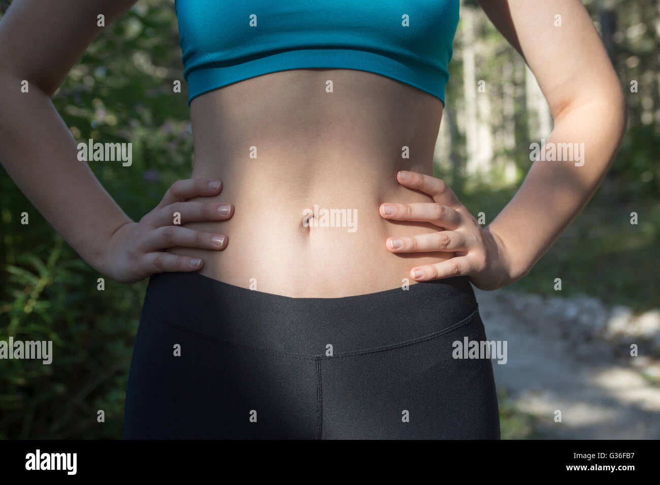 Mid section of fit woman's torso with her hands on hips. Female runner ...