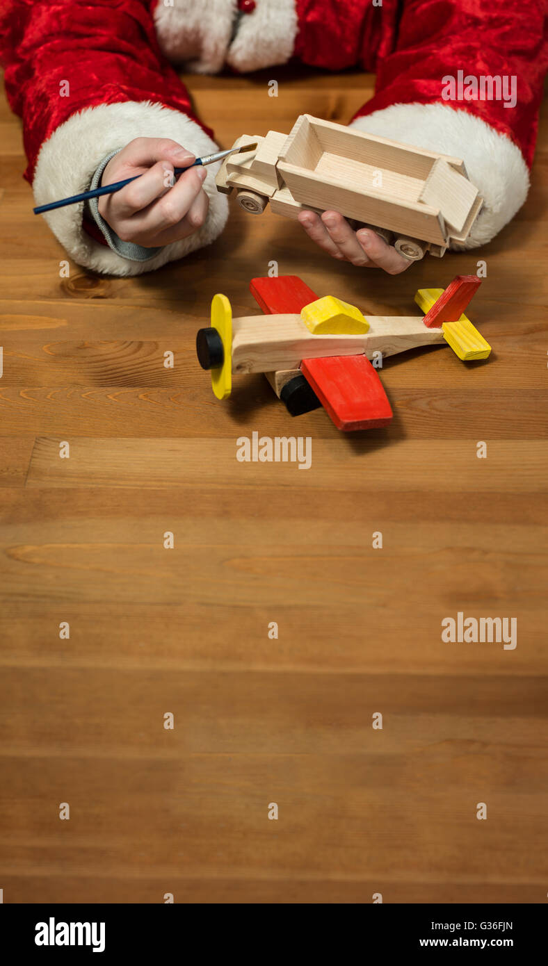 Santa Claus making toys. Painting and coloring wooden toy Stock Photo ...