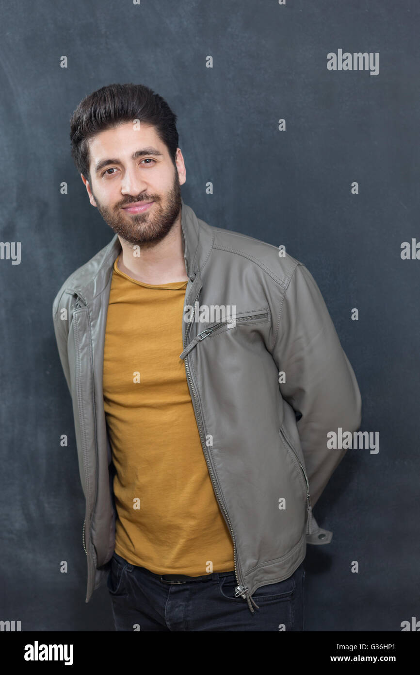 Looking cool and trendy. Handsome young bearded man posing against grey ...