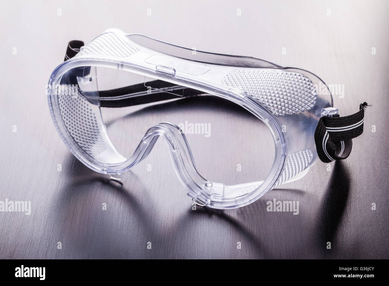clear safety protective glasses made of plastic on a dark wooden ...
