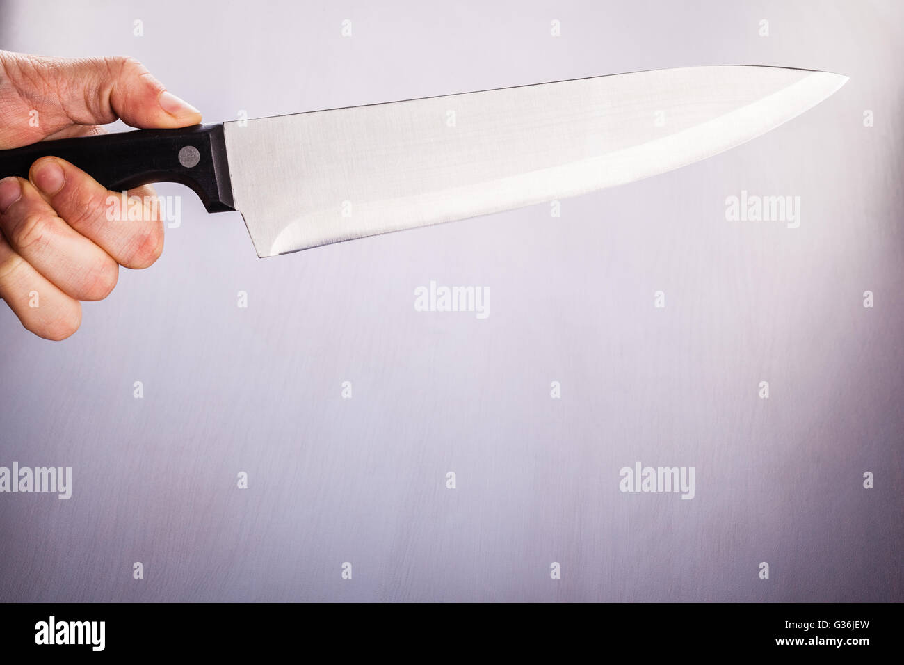 a male hand holding a big kitchen knife over a dark background Stock ...