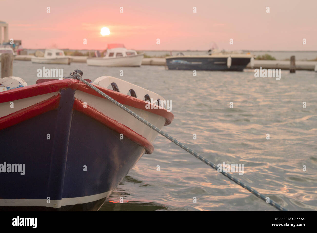 Rowboat docked in small harbor at sunset Stock Photo - Alamy