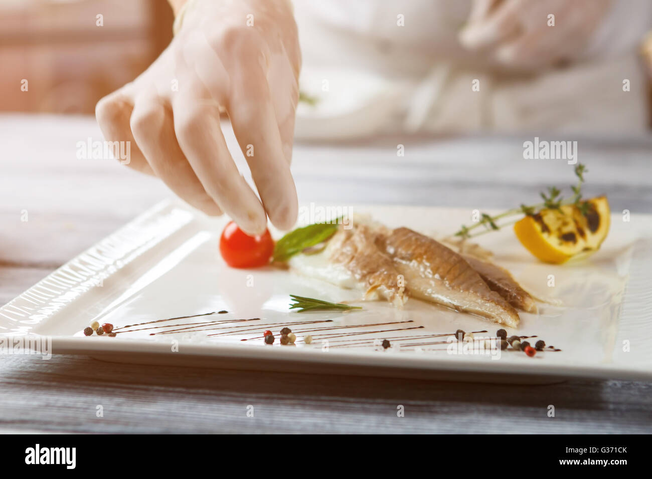 Hand over plate with fish Stock Photo - Alamy