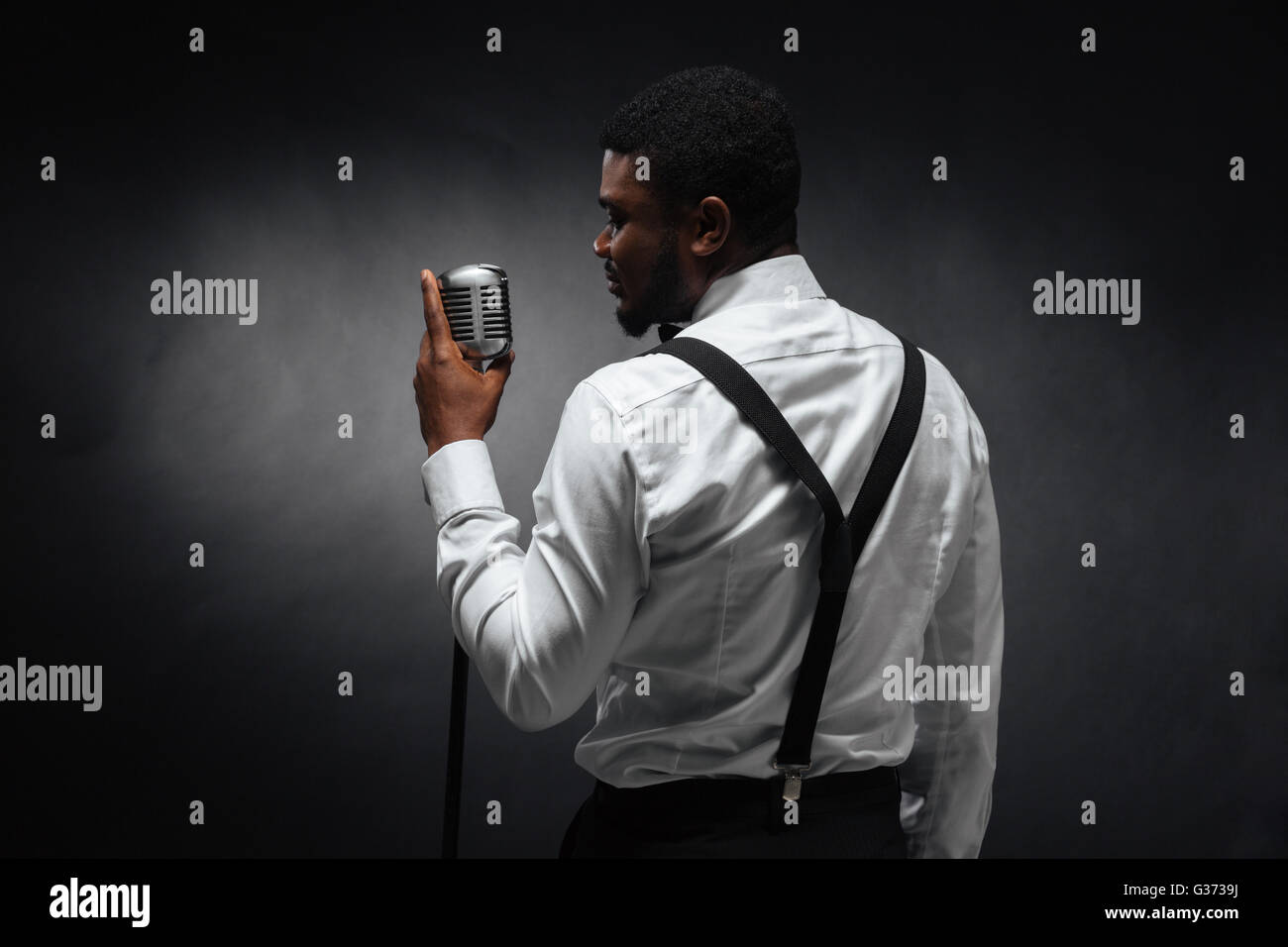 Back view portrait of afro american man singing into vintage microphone ...